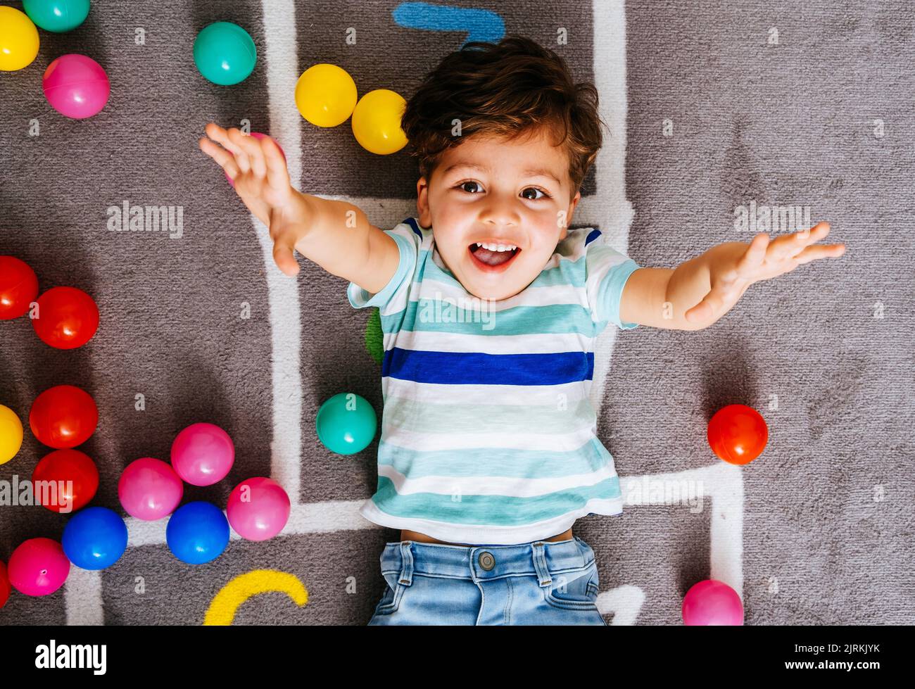 From above excited boy in casual clothes laughing and trowing up ...