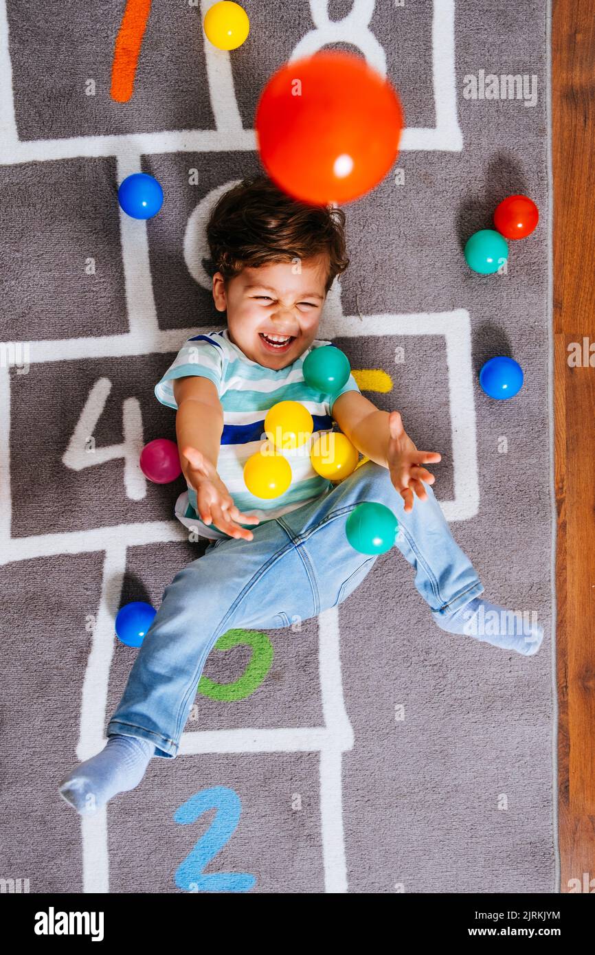 From above excited boy in casual clothes laughing and trowing up ...