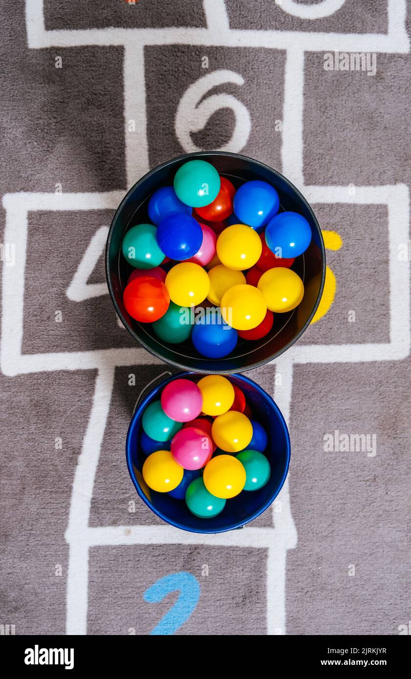 Top view of plastic buckets with multicolored balls placed on carpet ...