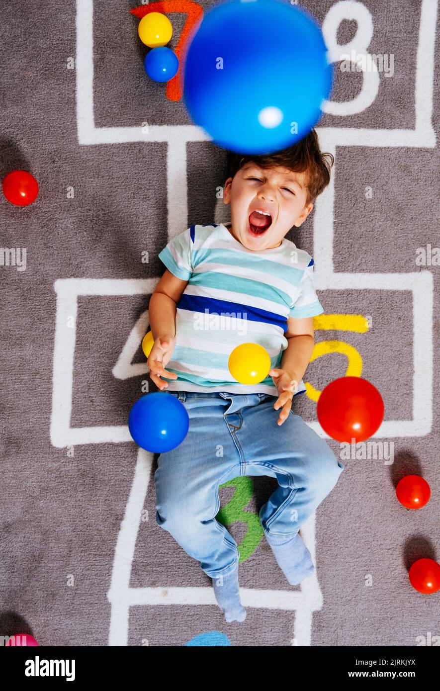From above excited boy in casual clothes laughing and trowing up ...