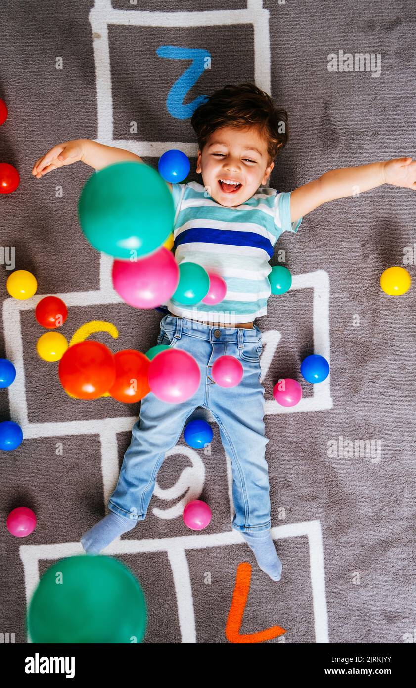From above excited boy in casual clothes laughing and trowing up ...