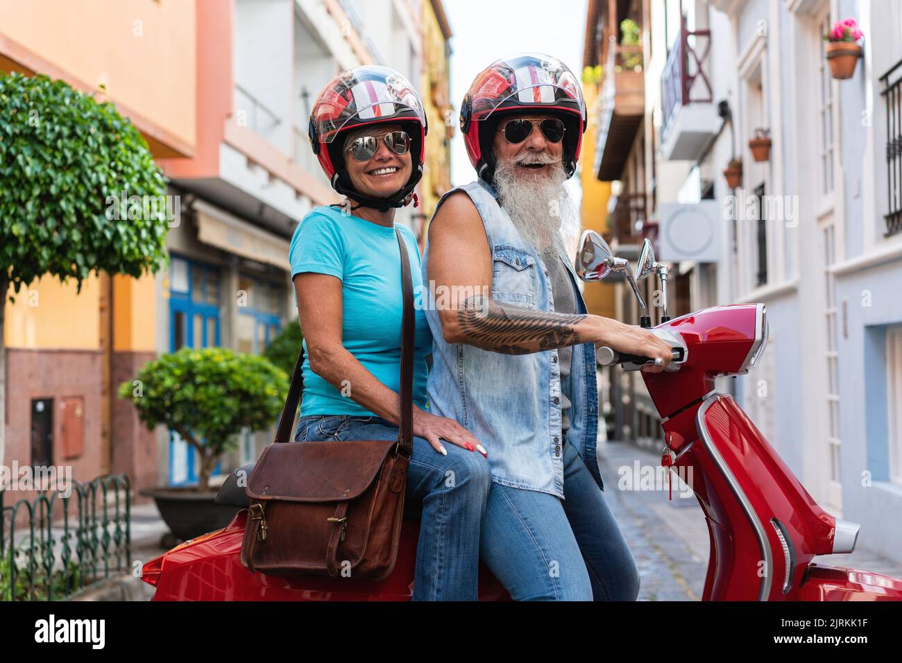 Side view of a modern senior couple with helmets and sunglasses riding ...
