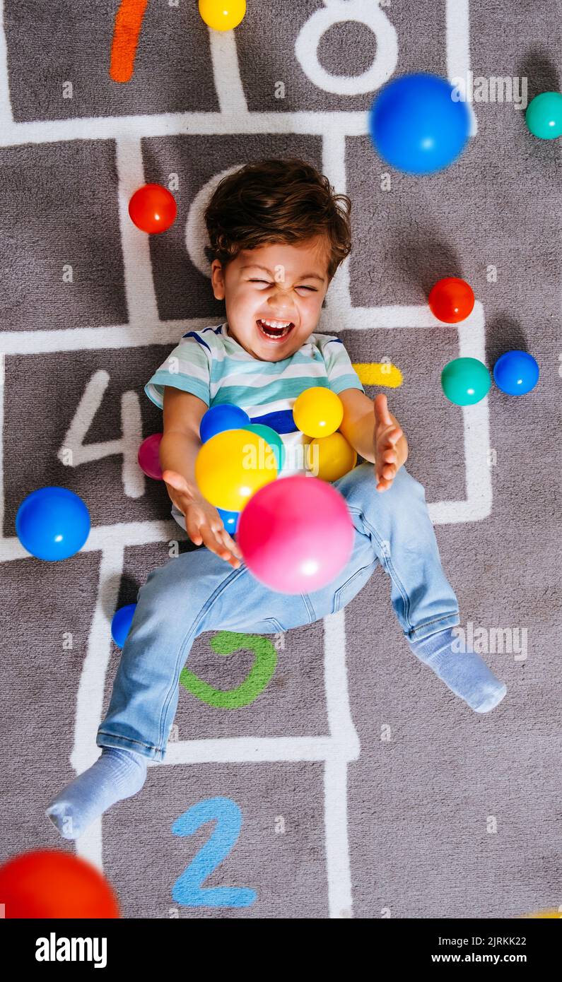 From above excited boy in casual clothes laughing and trowing up ...