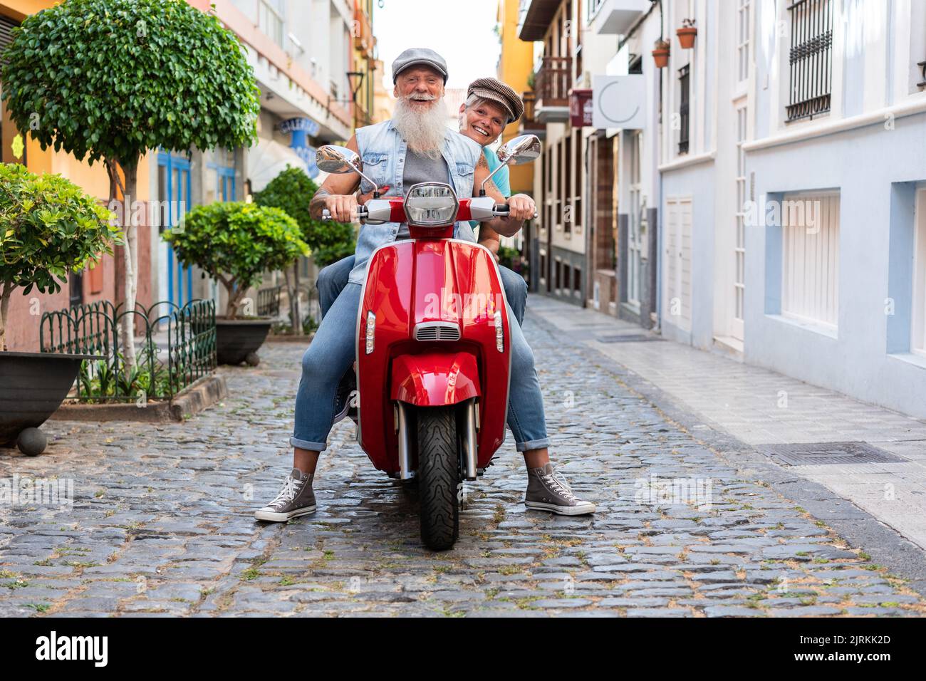 Front view of a modern senior couple riding on a motorcycle while ...