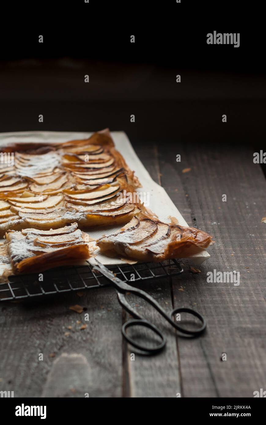 Closeup of cooling rack with frangipane apple pie on parchment lying on ...