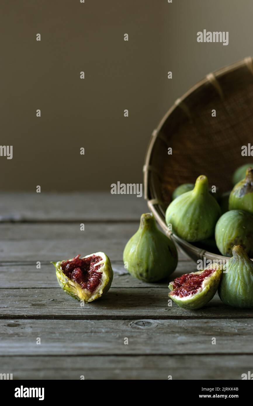 Closeup shot of basket with green figs and split fruit with red flesh ...