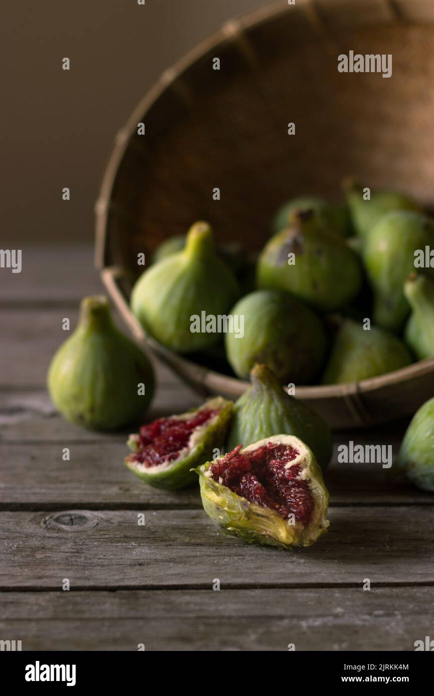 Closeup shot of basket with green figs and split fruit with red flesh ...