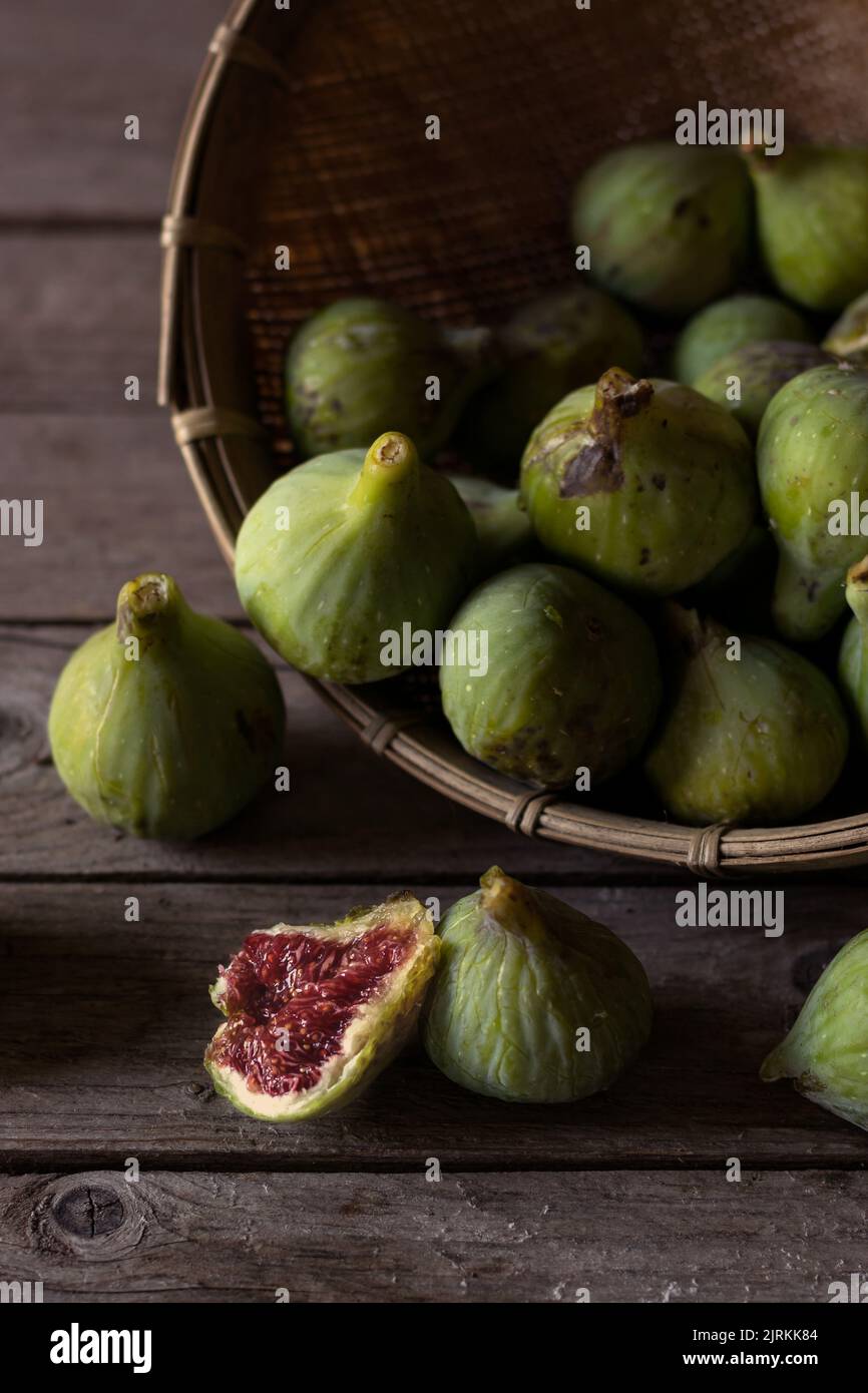 Closeup shot of basket with green figs and split fruit with red flesh ...
