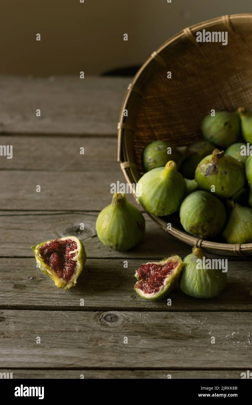 Closeup shot of basket with green figs and split fruit with red flesh ...