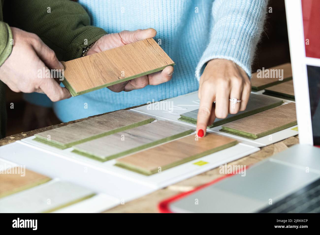 Cropped unrecognizable craftsman helping female client in picking ...