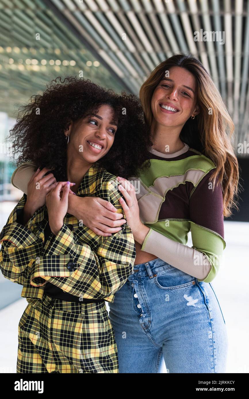 Young smiling woman embracing cheerful ethnic girlfriend with Afro ...