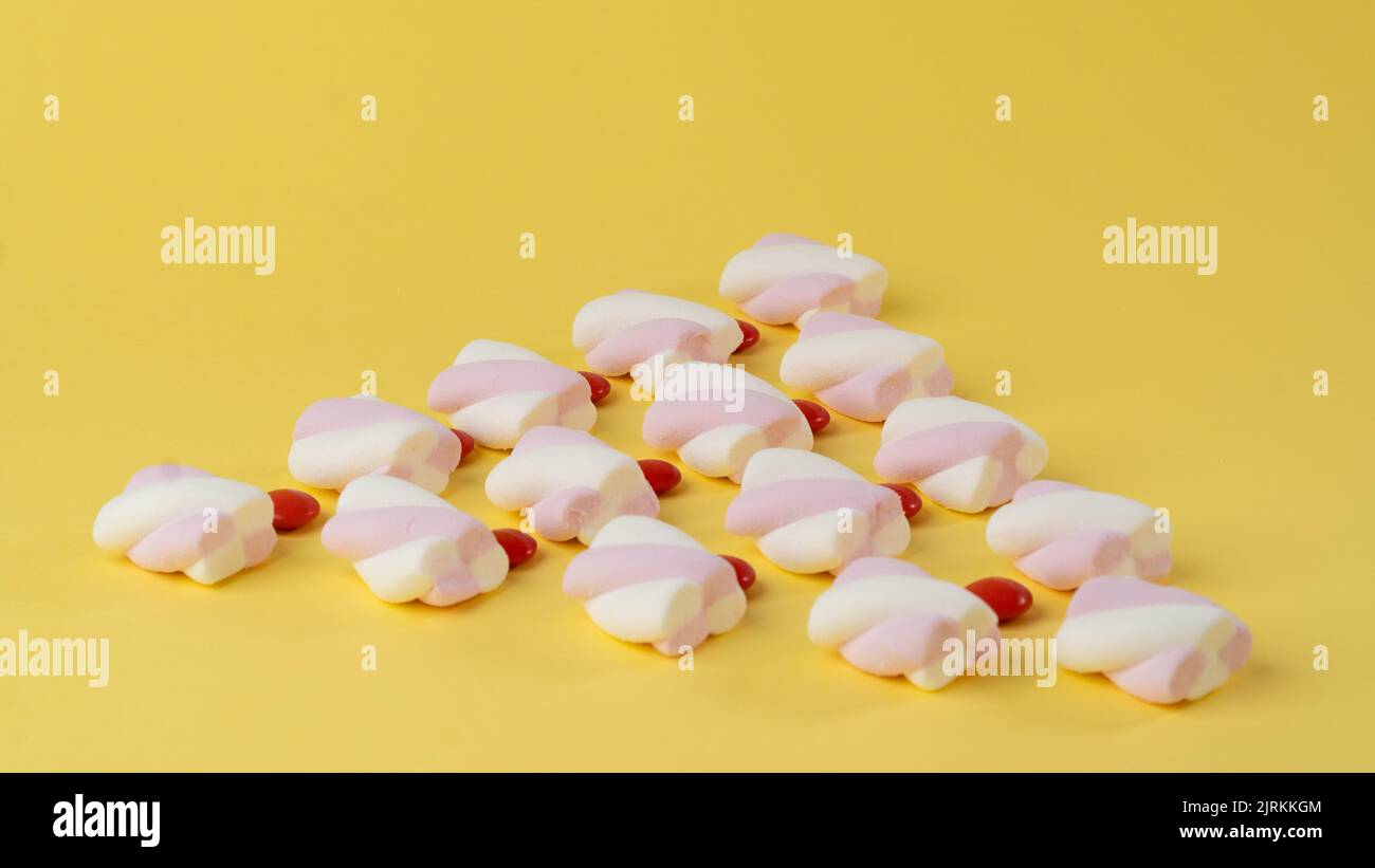 Marshmallows and red candy dragees in the form of a triangle on a ...