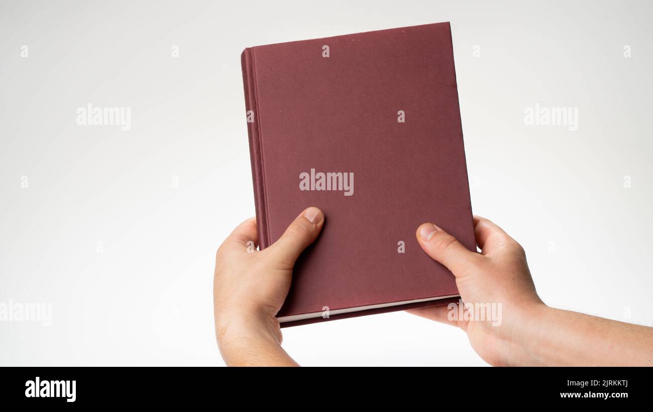 Men's hands hold a book or notebook in a burgundy binding on a white ...