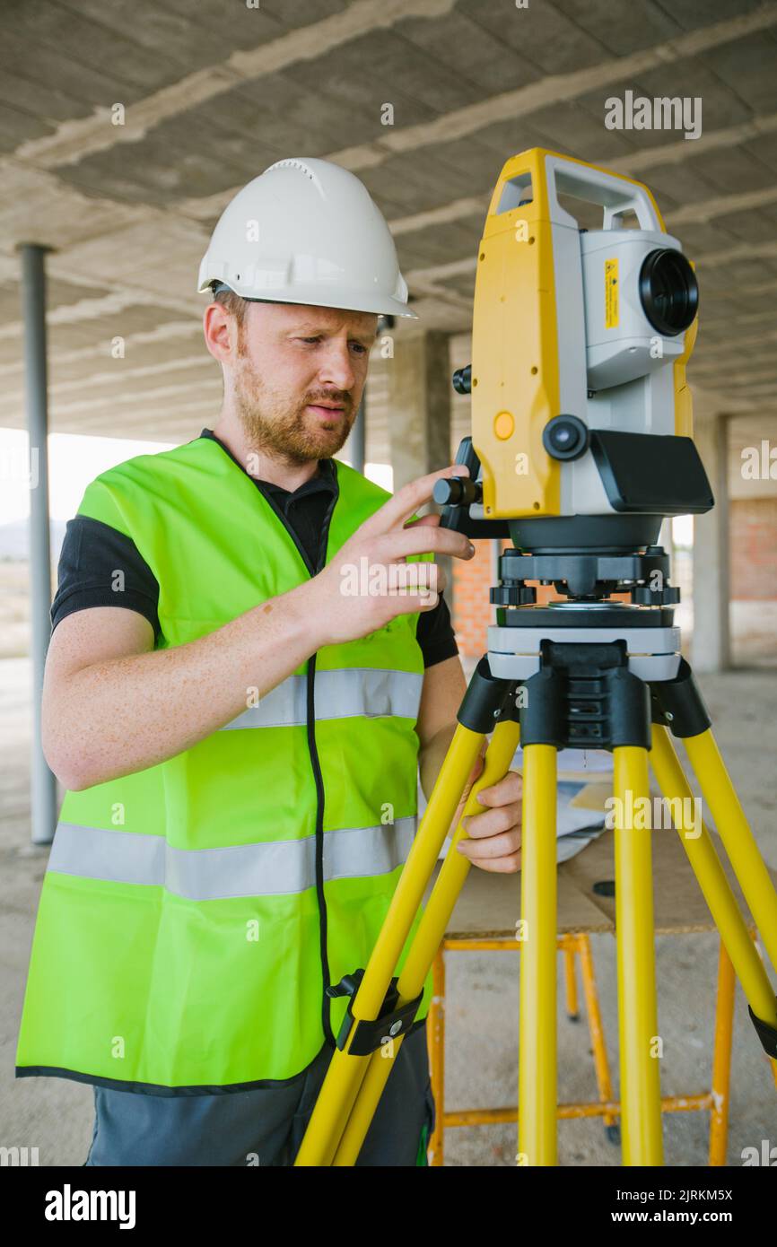Surveyor engineer working at construction site with measuring equipment ...