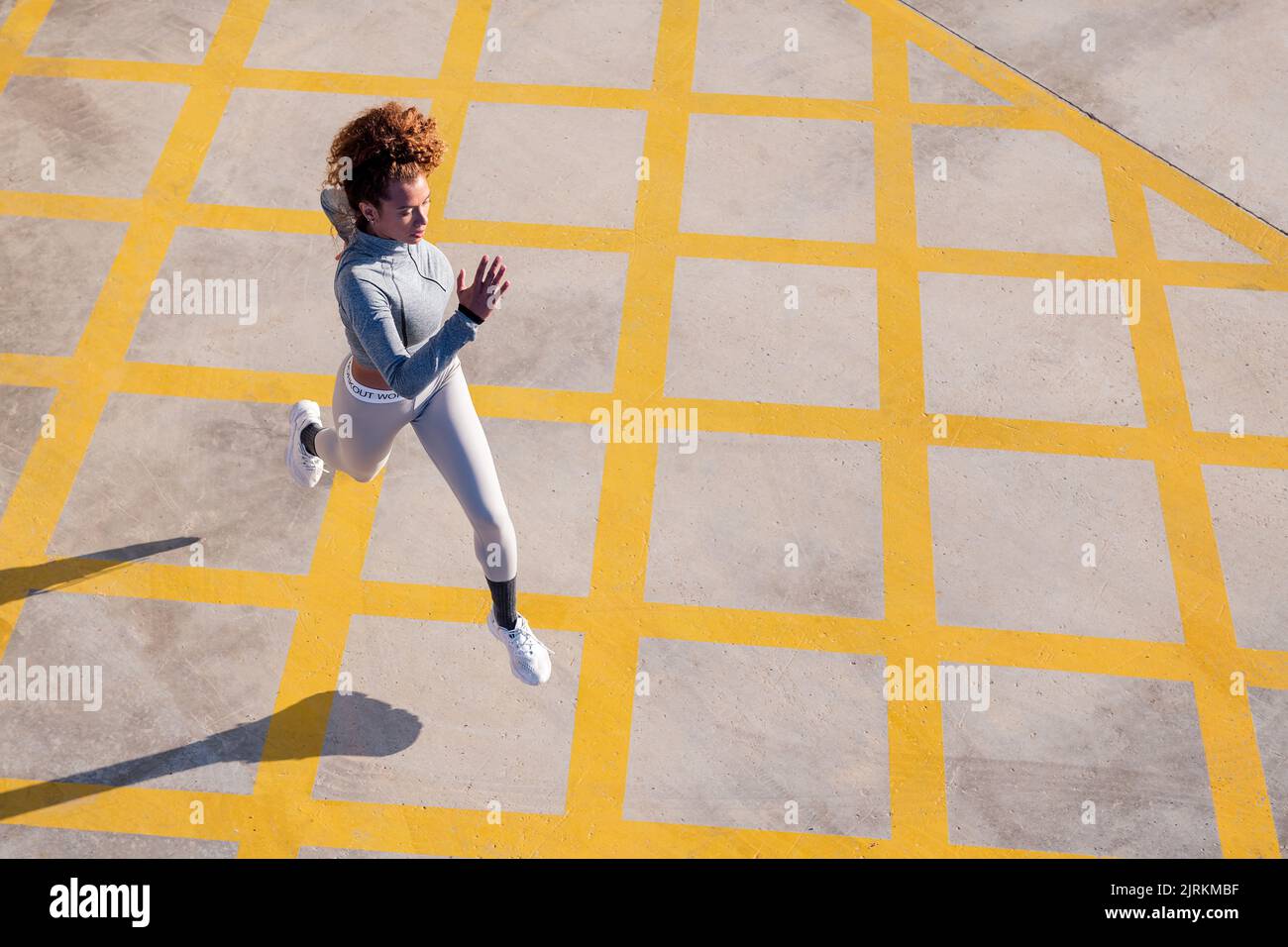 From above of determined female jogger in activewear running on ...