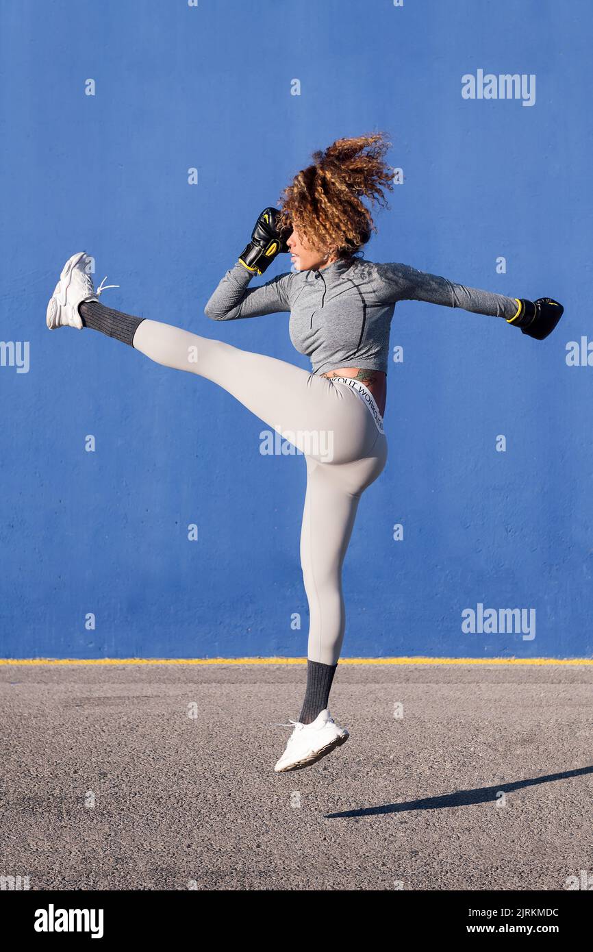 Side view of flexible female fighter in sportswear and boxing gloves ...