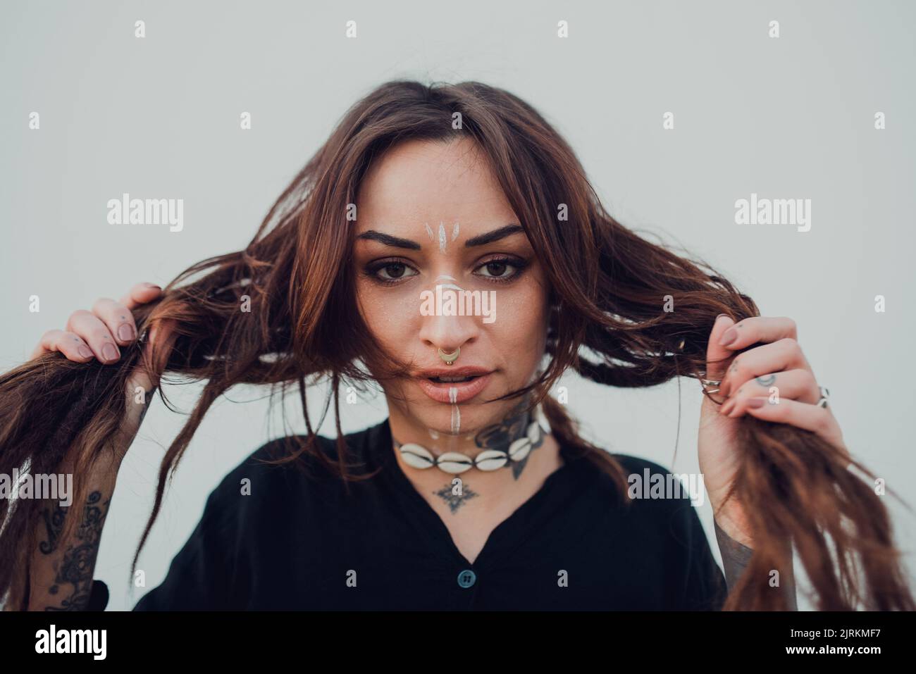 Confident stylish female with white ritual makeup and tattoos in black ...