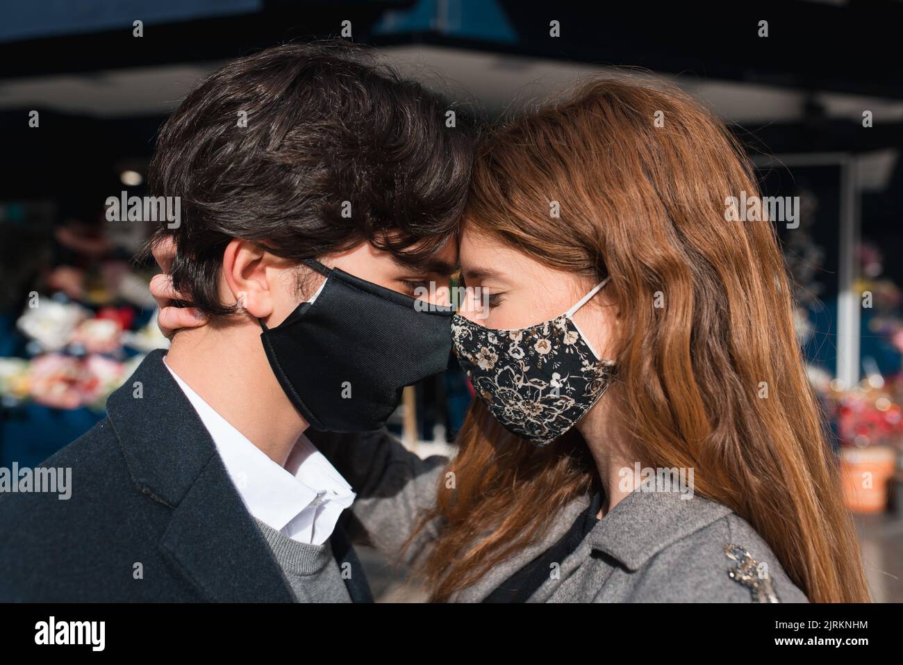 Side view of happy young couple in love wearing protective masks ...