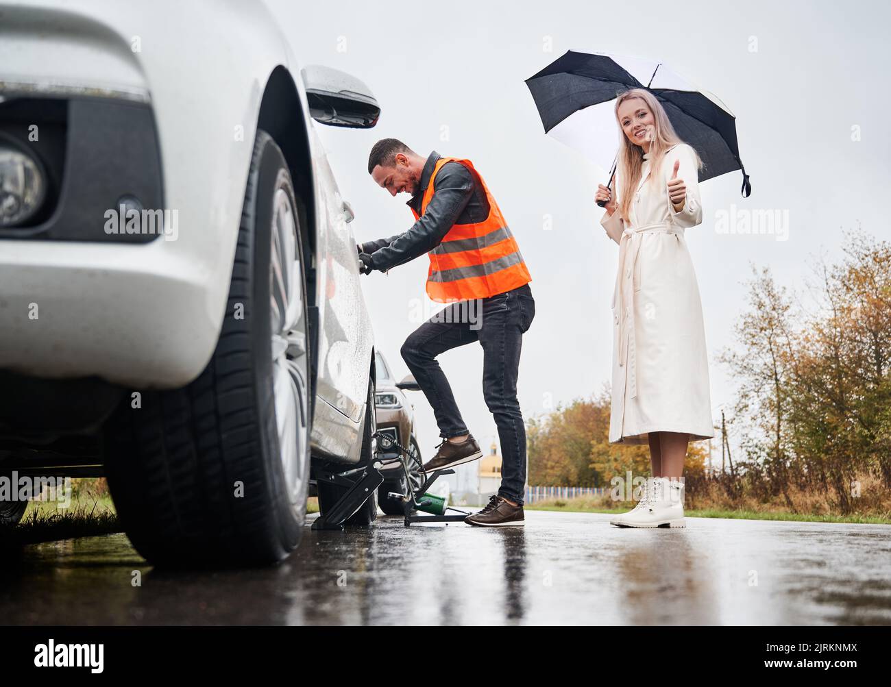 Beautiful young woman with umbrella giving thumbs up and smiling while ...