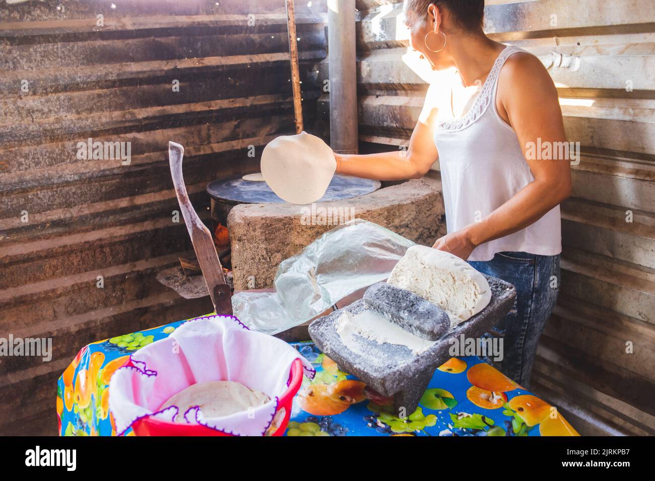 A Hispanic woman cooking corn dough on a stove, making homemade ...