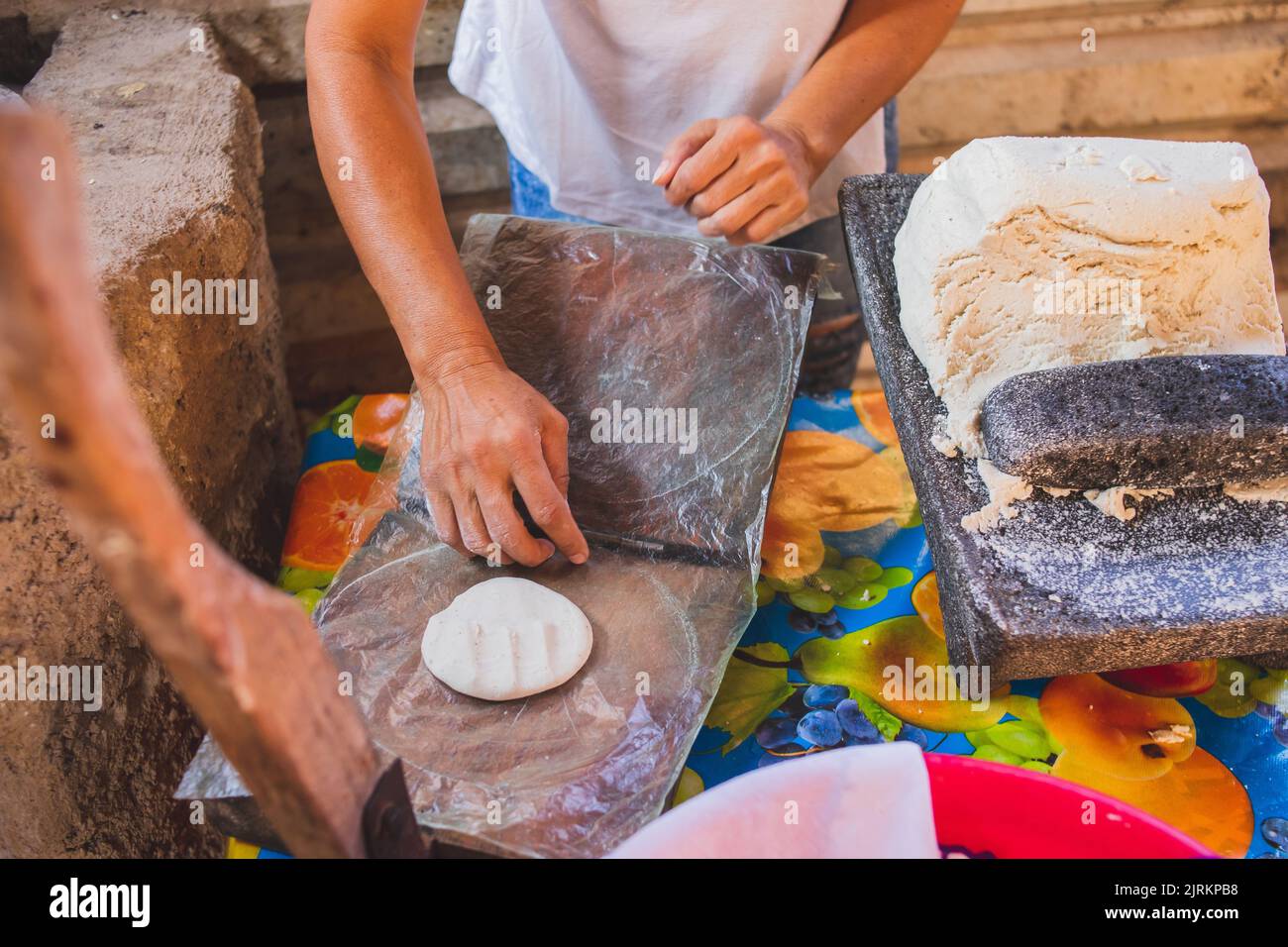 A Hispanic woman kneading corn dough on a metate to make homemade ...