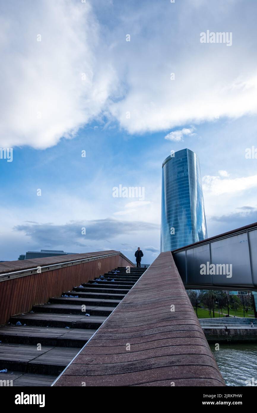 A lone person climbing up a staircase going up towards a skyscraper on ...