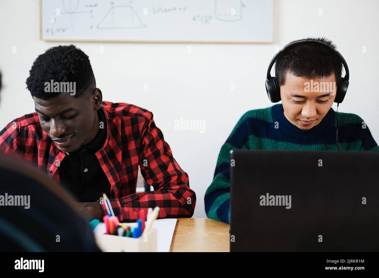 Multiracial students using laptop computers while studying together at ...
