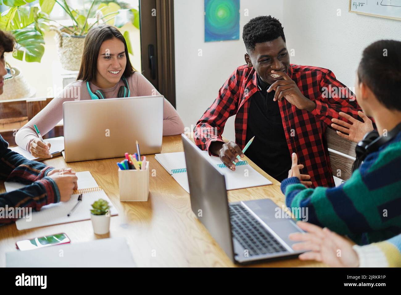 Multiracial students reading books and using laptop computers while ...