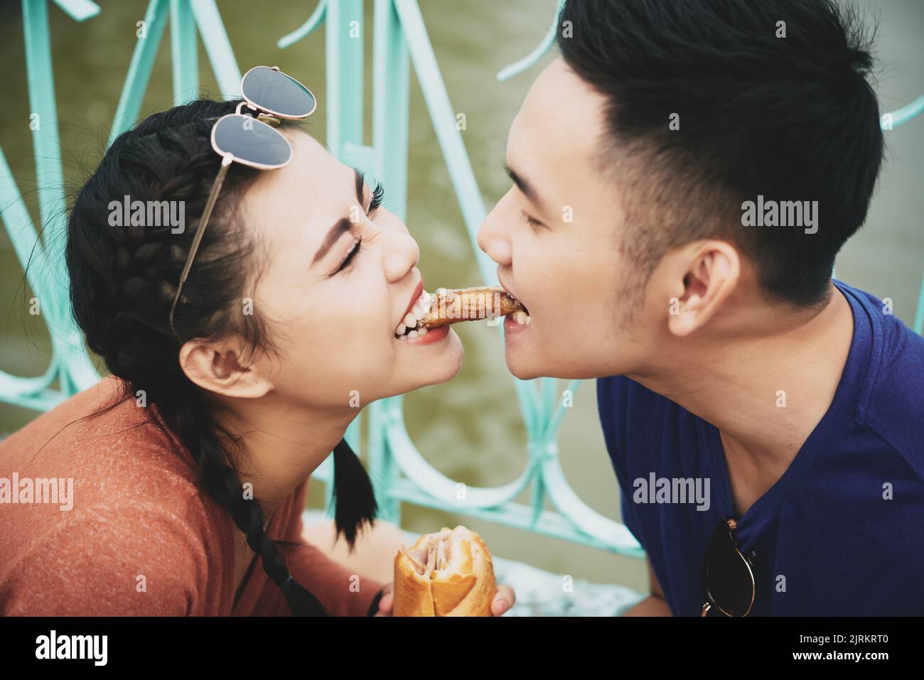 Joyful young Asian couple sharing the last piece of chicken Stock Photo ...