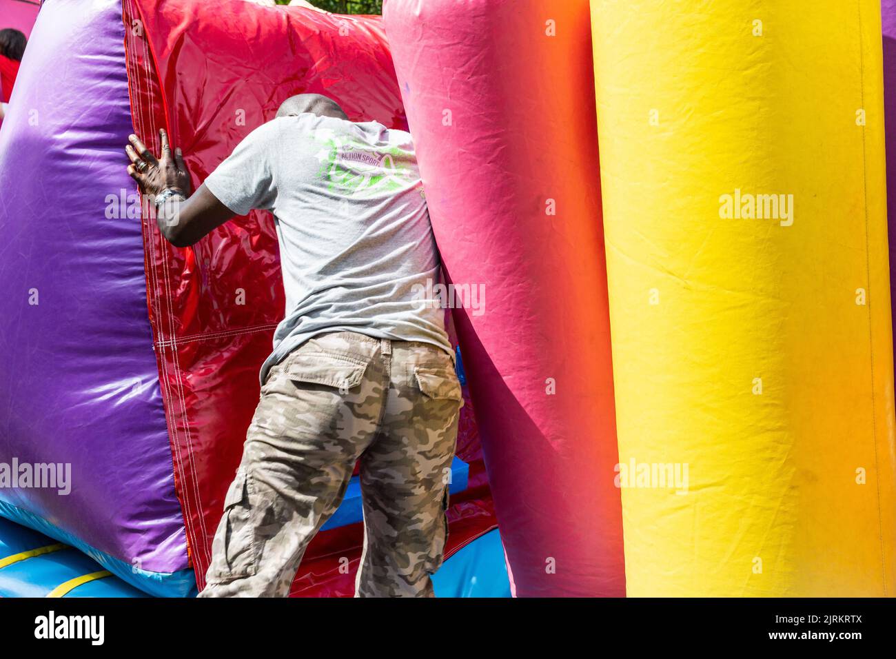 Man directing a multicolored bouncy castle in the process of inflation ...