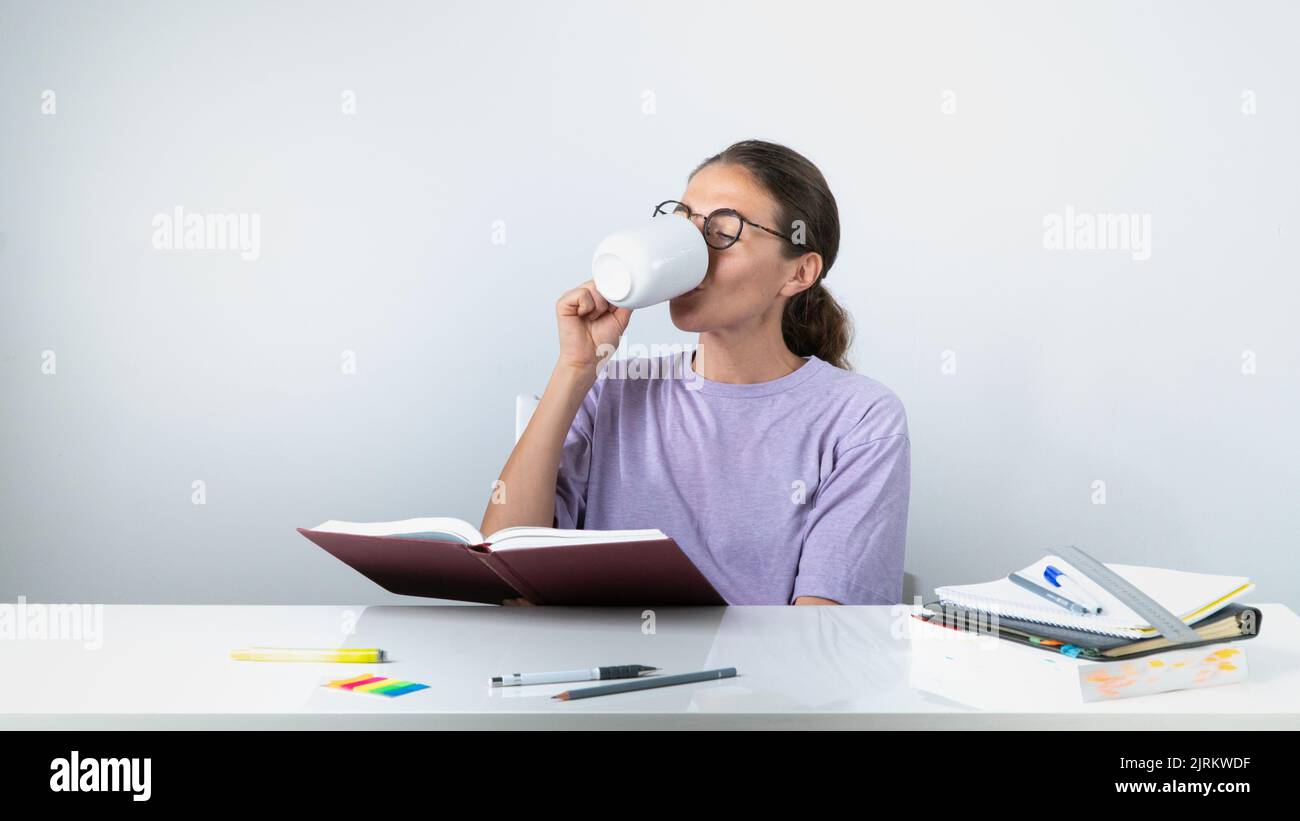 A student learns lessons and drinks tea while reading a textbook - a ...