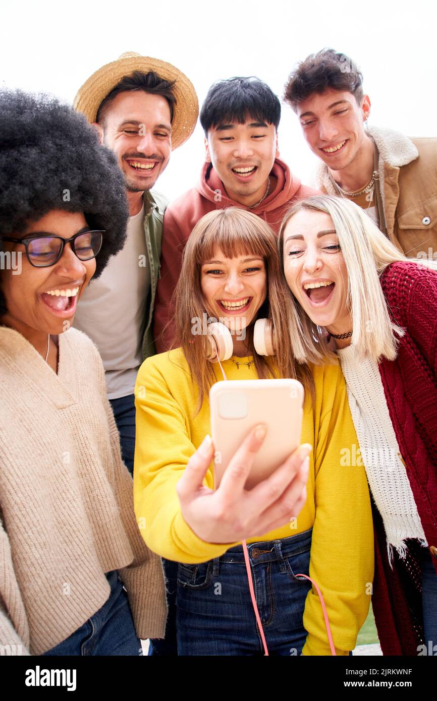 Vertical photo. Multicultural group of friends using cell phones and ...