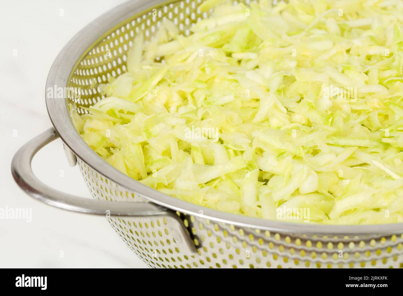 Close up of grated salted zucchini placed in a steel microperforated ...