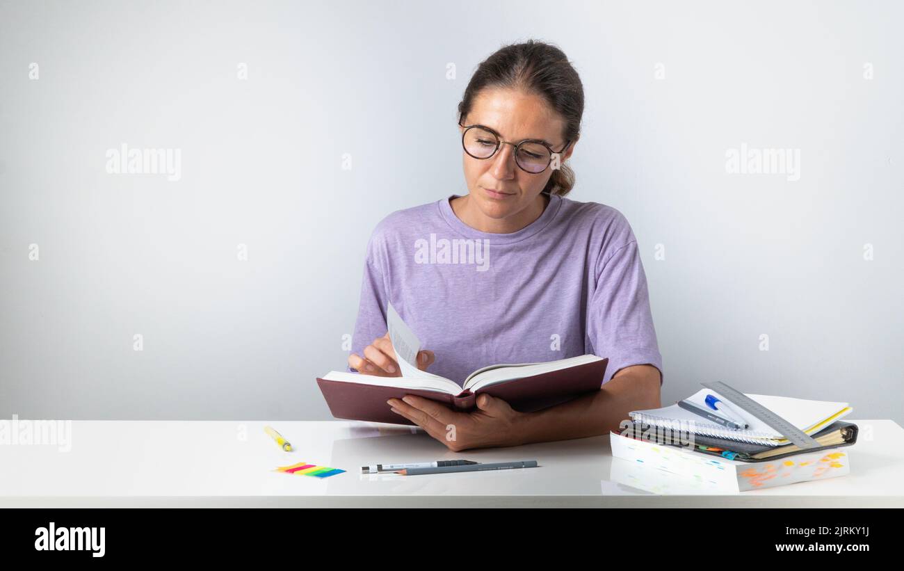 Studying the material, a student with glasses reads a textbook at the table Stock Photo - Alamy