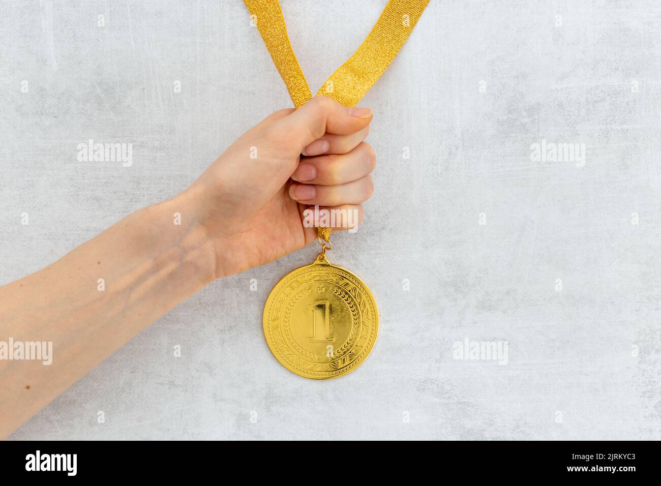 Hand holding up gold medal first place. Winner concept Stock Photo - Alamy