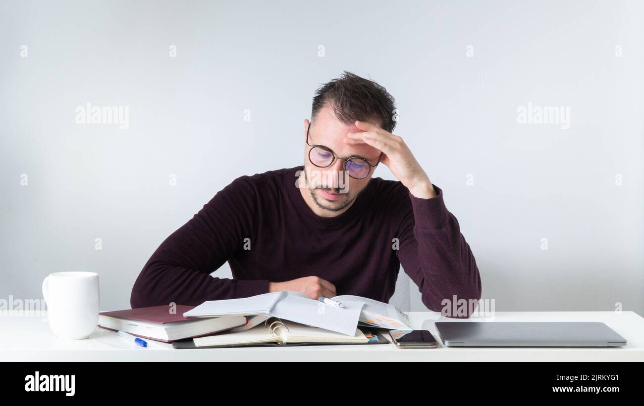 A man with glasses at his desk thinks about a task in the office - to ...