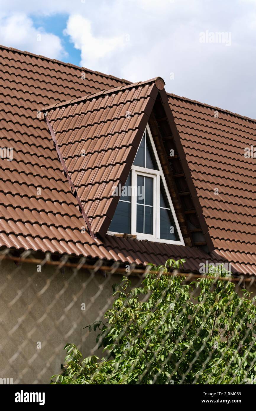 Close up shot of a triangular window on a metal tile shingles roof ...