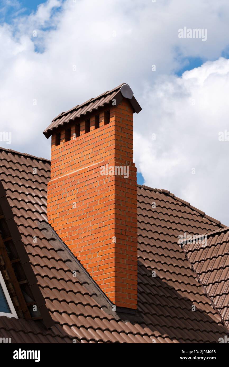 Close up shot of a chimney on a metal tile shingles roof against blue ...