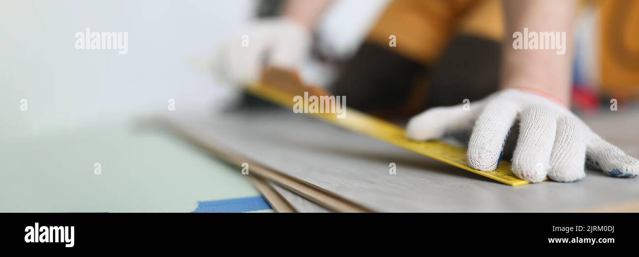Man builder measuring laminate board with ruler for laying floor ...