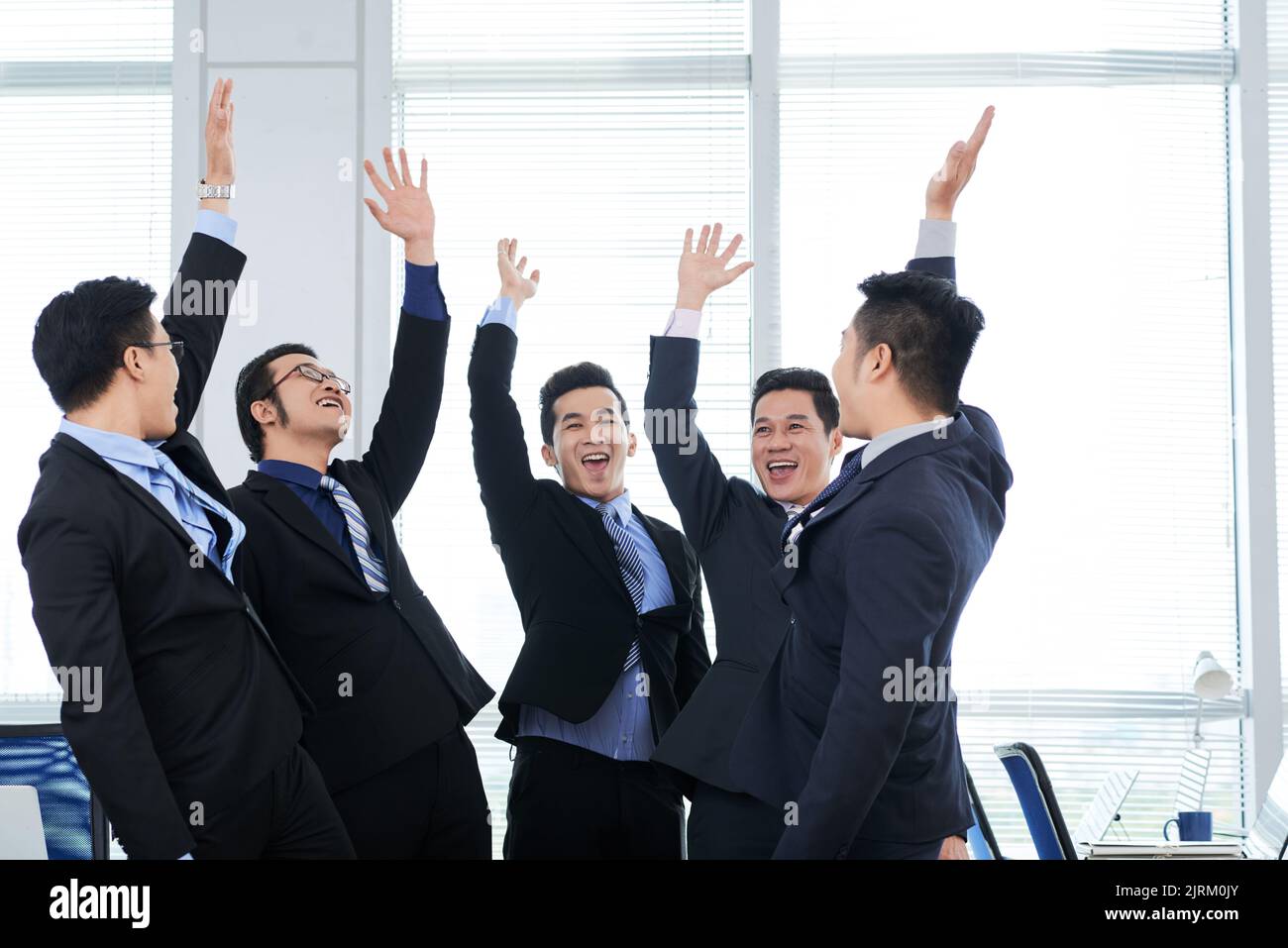 Group of cheerful managers wearing classical suits standing in circle ...
