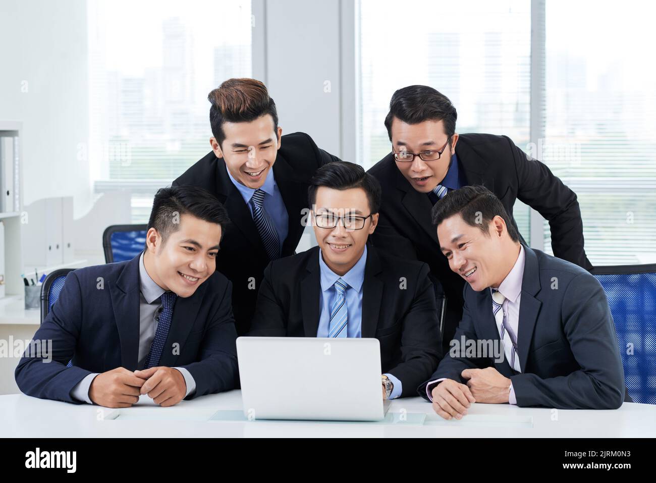 Group of smiling Asian managers wearing classical suits gathered ...