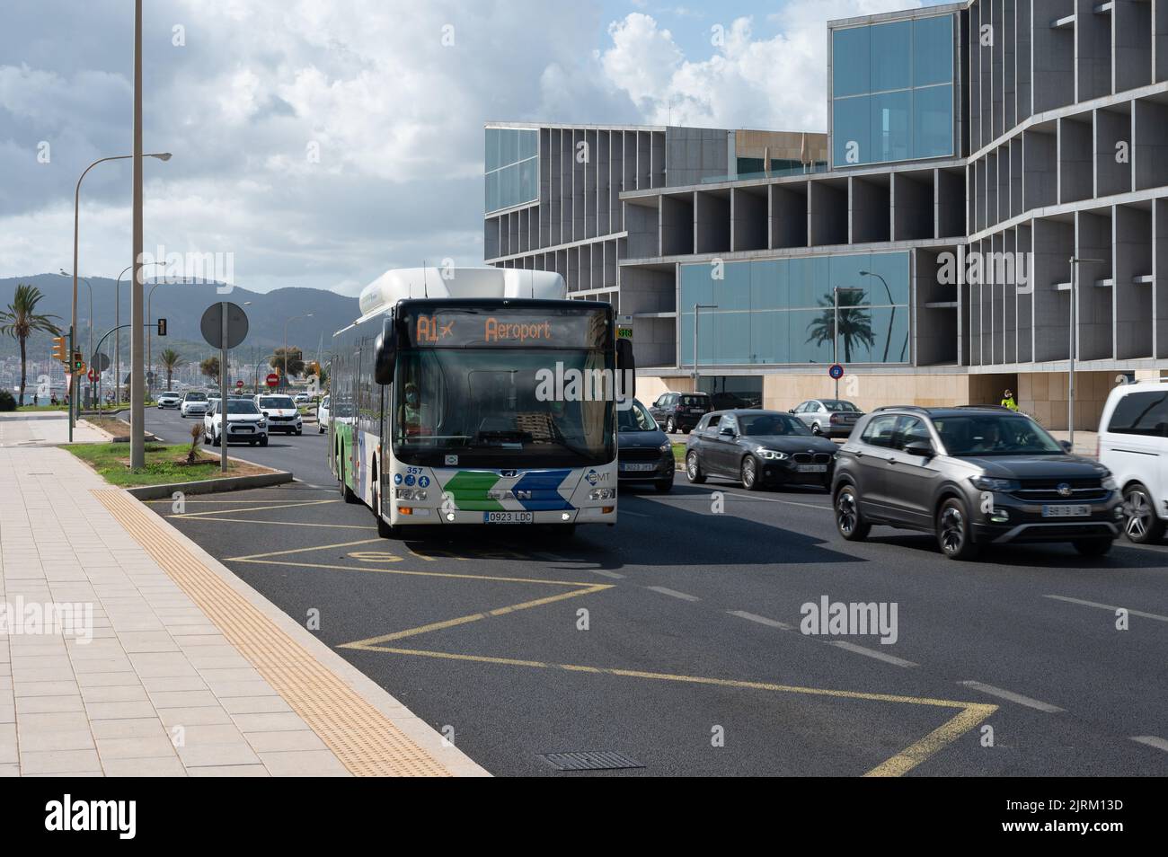 An urban bus driving passengers to the airport on a road with cars near ...