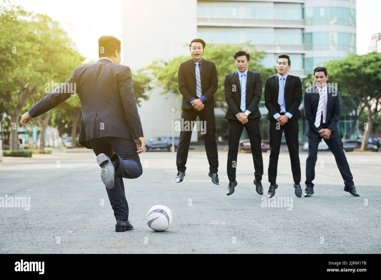 Four Asian white collar workers wearing classical suits forming wall to ...