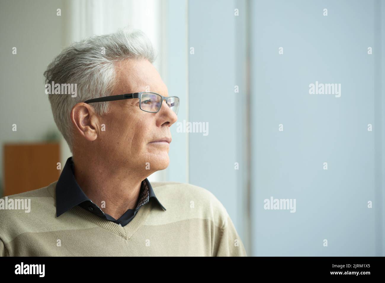 Portrait of pensive senior man looking through window Stock Photo - Alamy