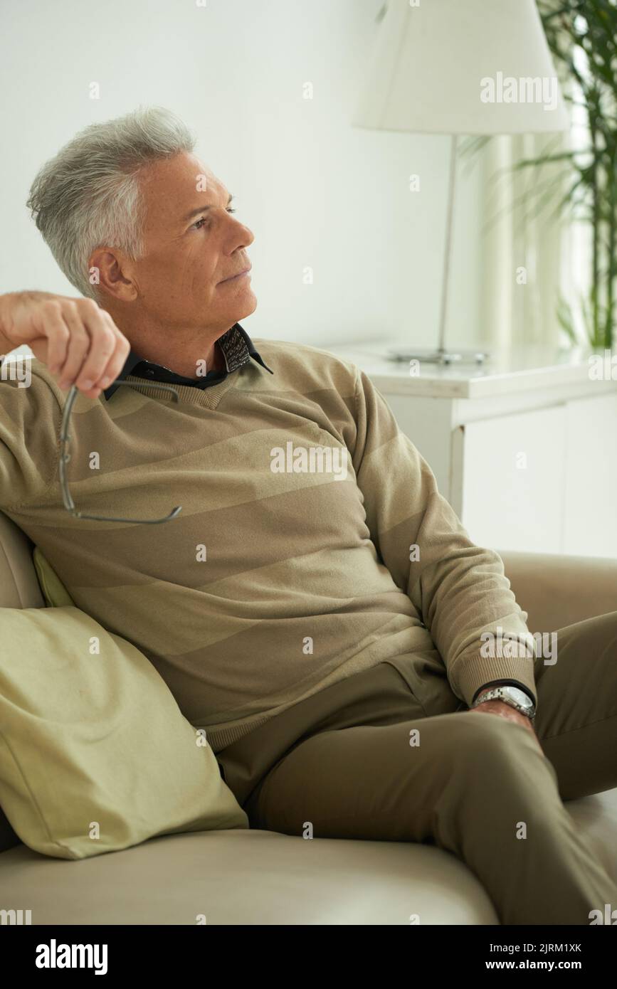 Elderly man sitting on sofa deep in thoughts Stock Photo - Alamy