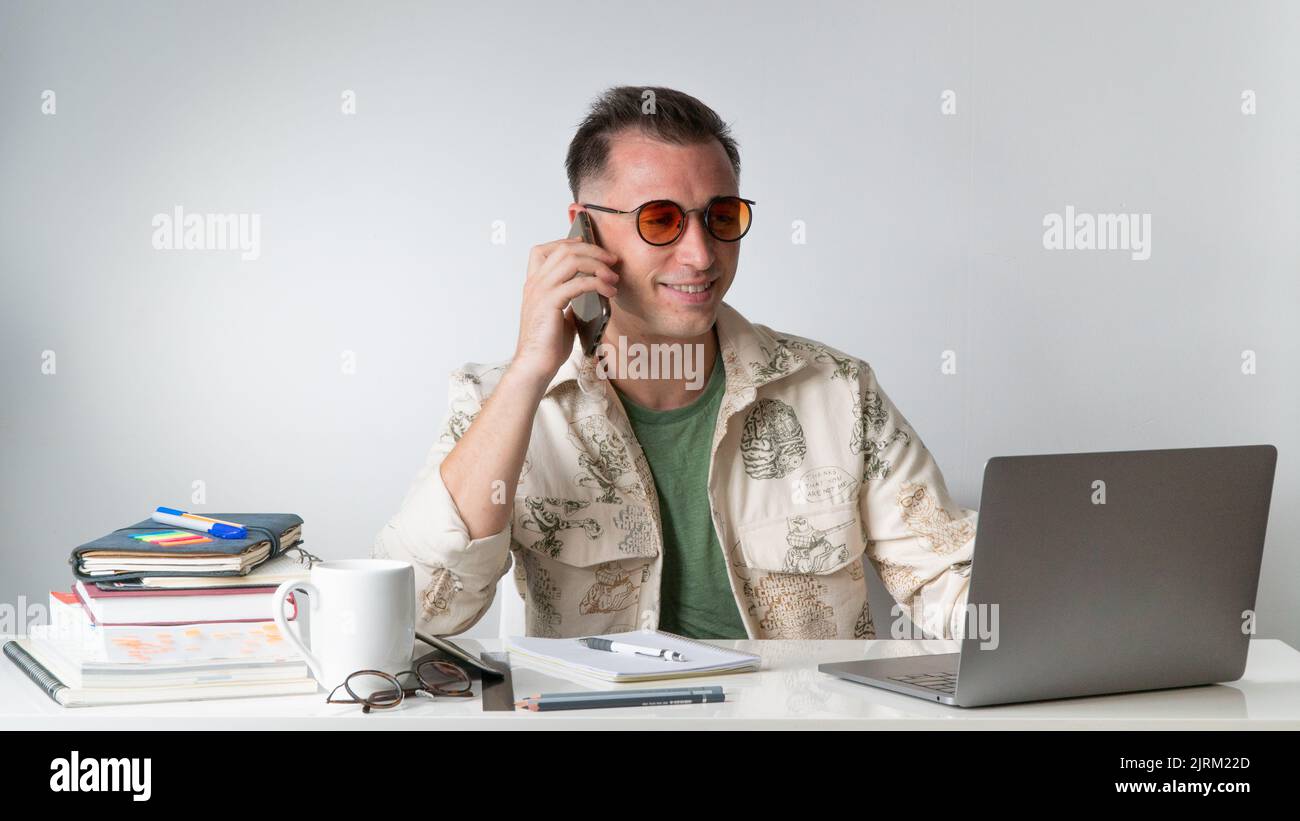 A student or employee talks on a smartphone at their desk Stock Photo ...