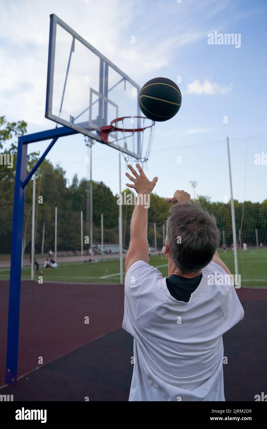 Man is throwing ball to the hoop. Training of basketball on the street ...