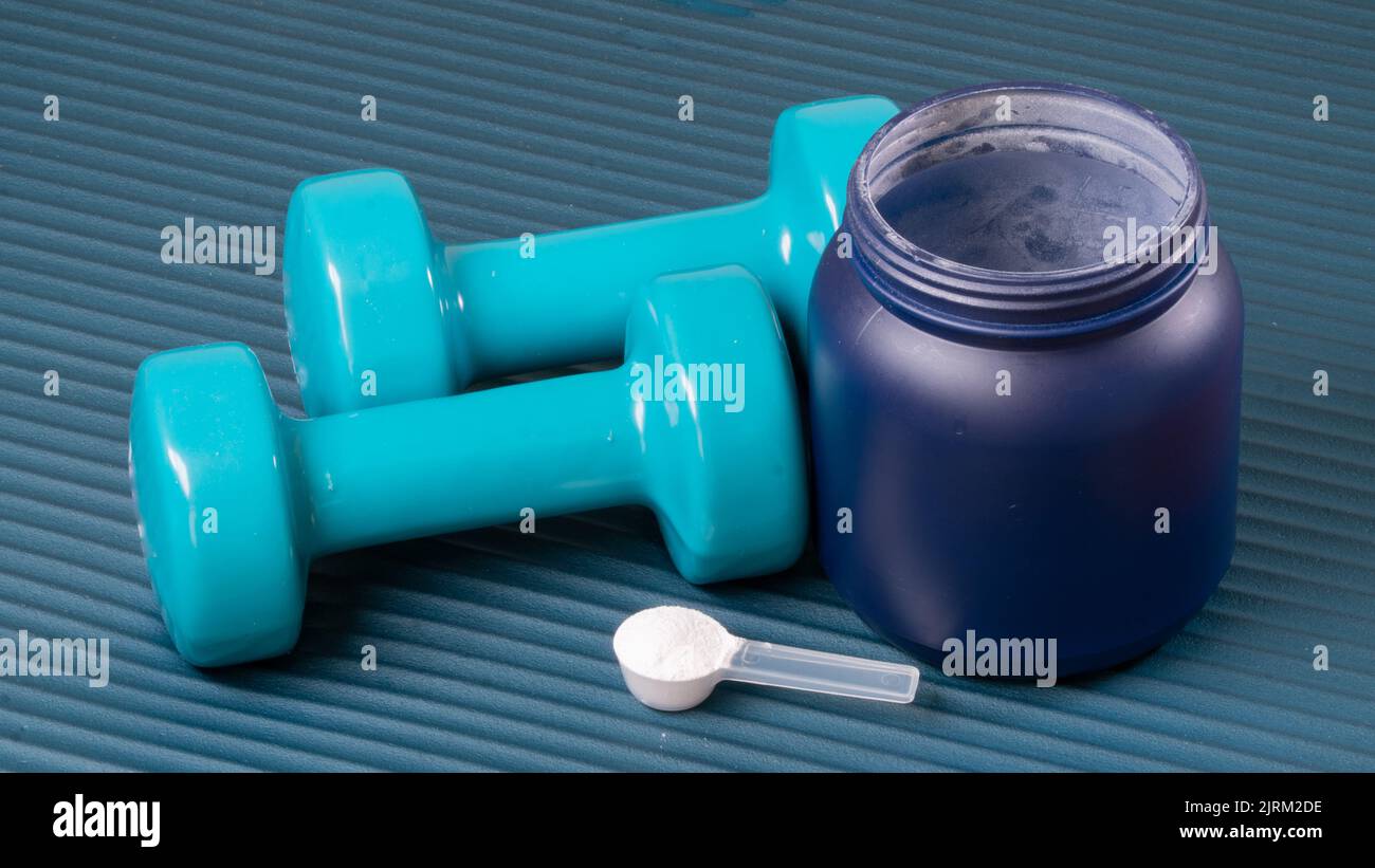 Sports nutrition and dumbbells on the mat for training Stock Photo - Alamy
