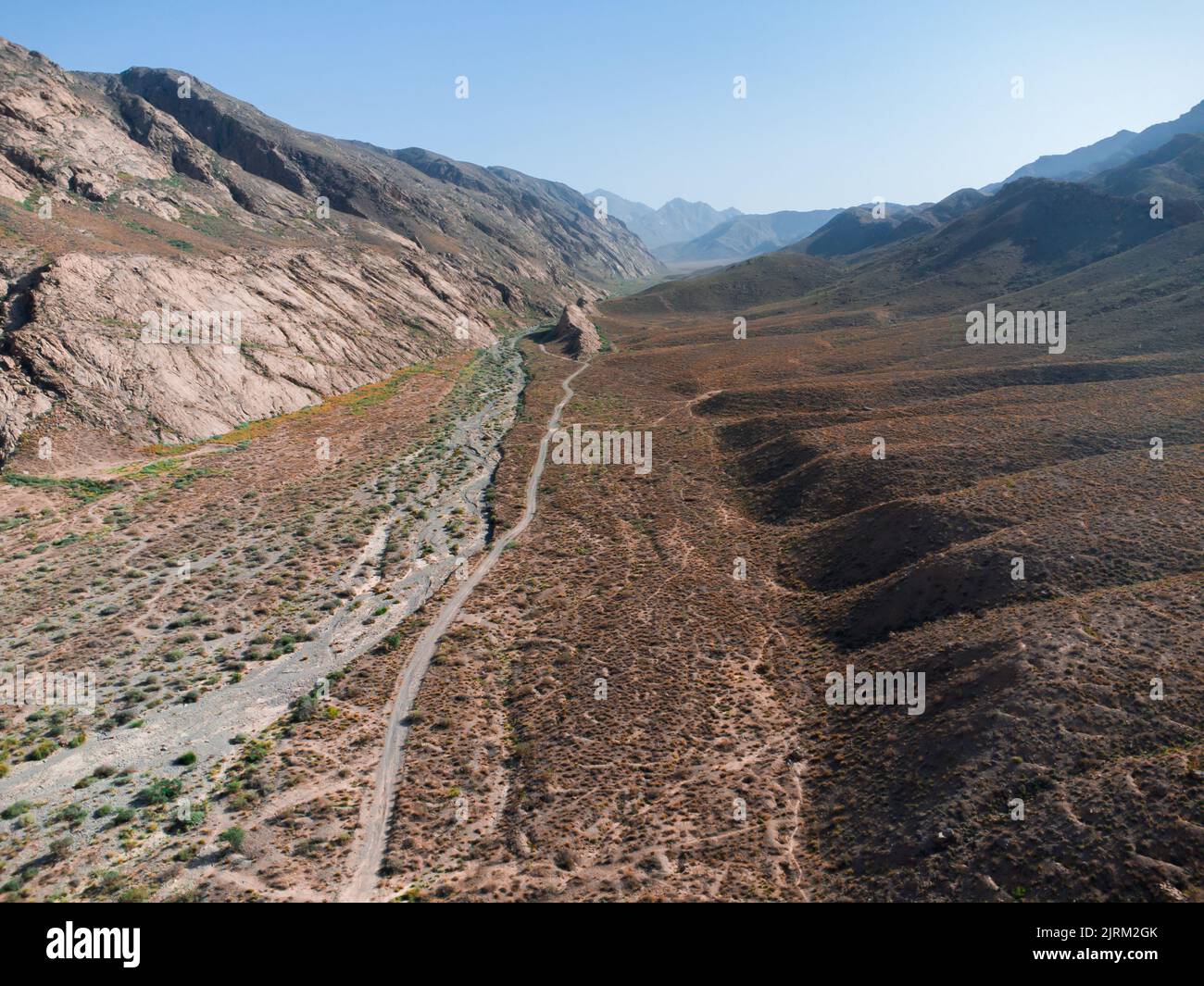 A deserted mountain chain with a thin road passing through one end to ...