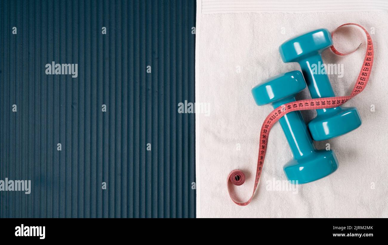 Measuring tape centimeter with dumbbells and towel on the mat for ...